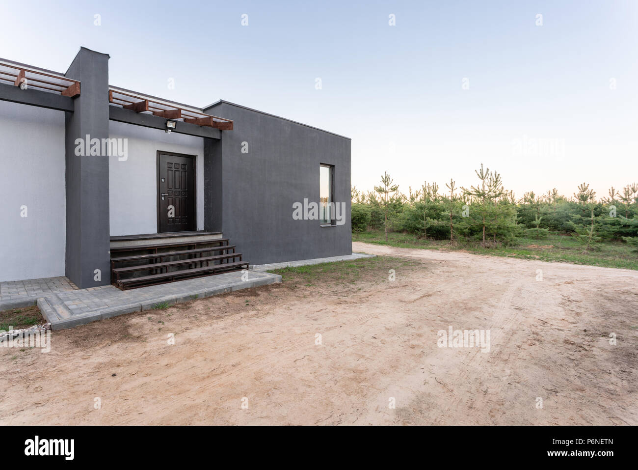 Side view of an open veranda in front of a modern forest cottage. Pine ...