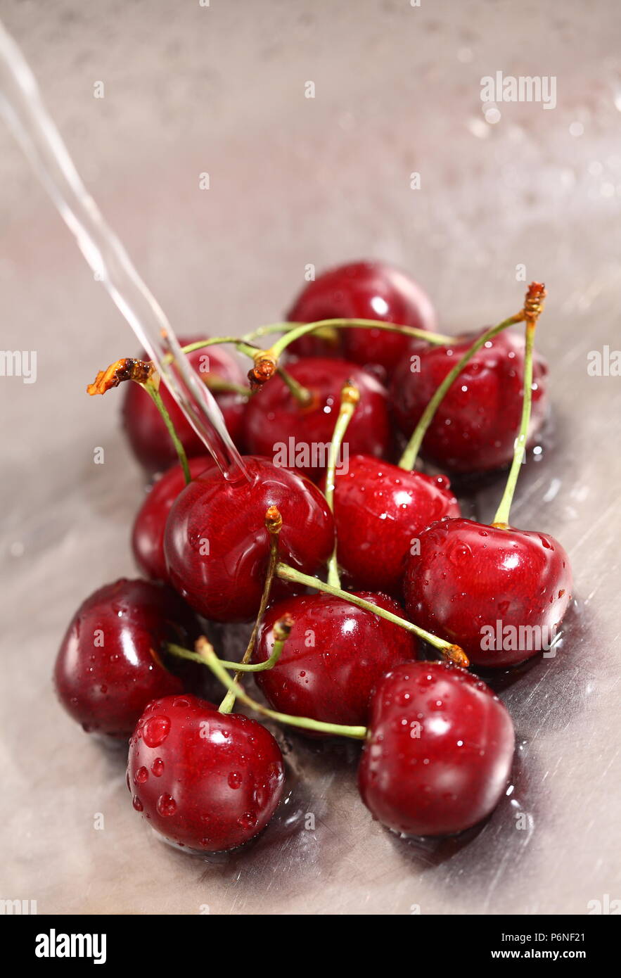 Washing sweet cherries in metal kitchen sink under water jet close-up ...