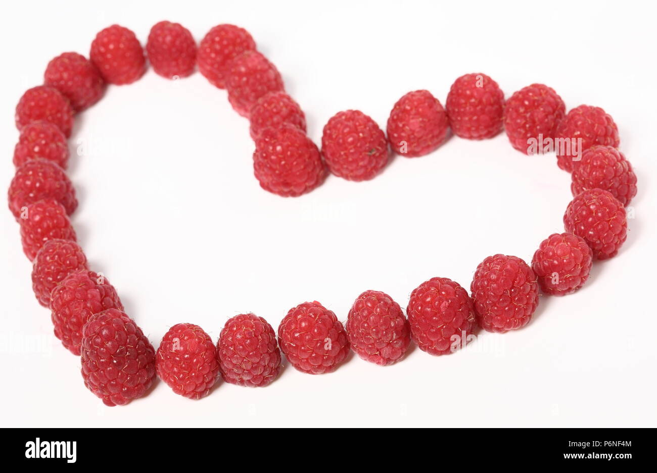 Heart made out of raspberries over white background Stock Photo - Alamy