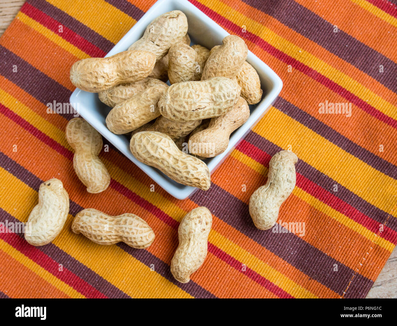 Unpeeled peanuts on white container Stock Photo - Alamy