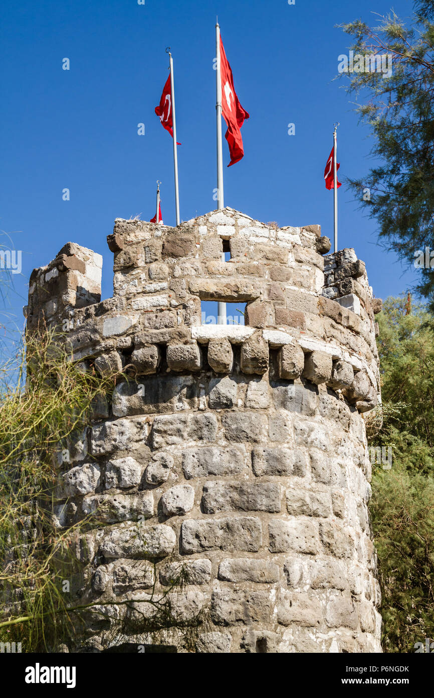 Tower of Bodrum castle with Turkish flags on pole against blue sky ...