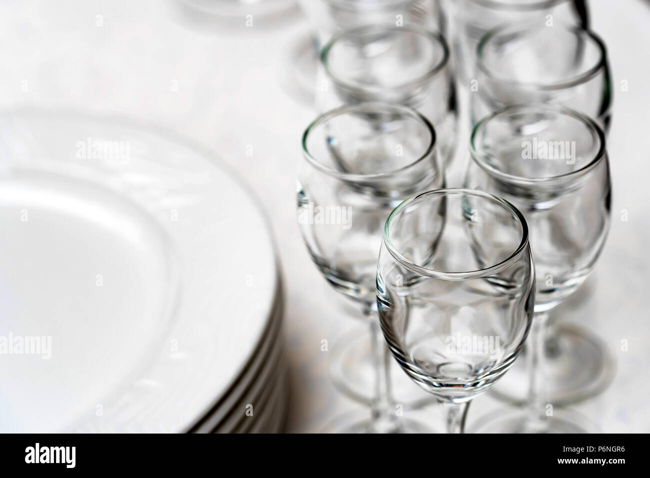 Stack of white plates and empty wine glasses Stock Photo - Alamy