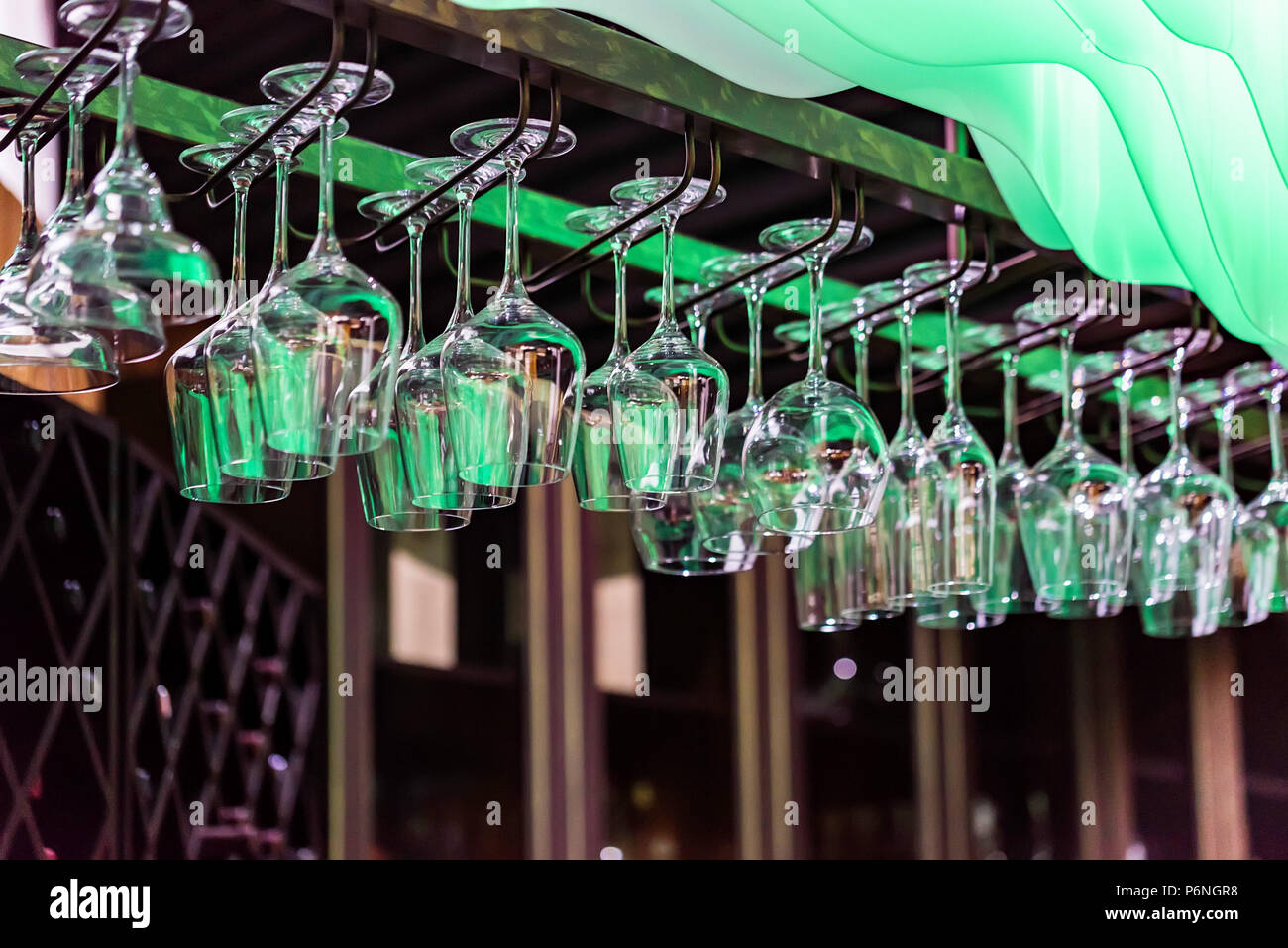 Empty glasses hang over bar rack Stock Photo - Alamy