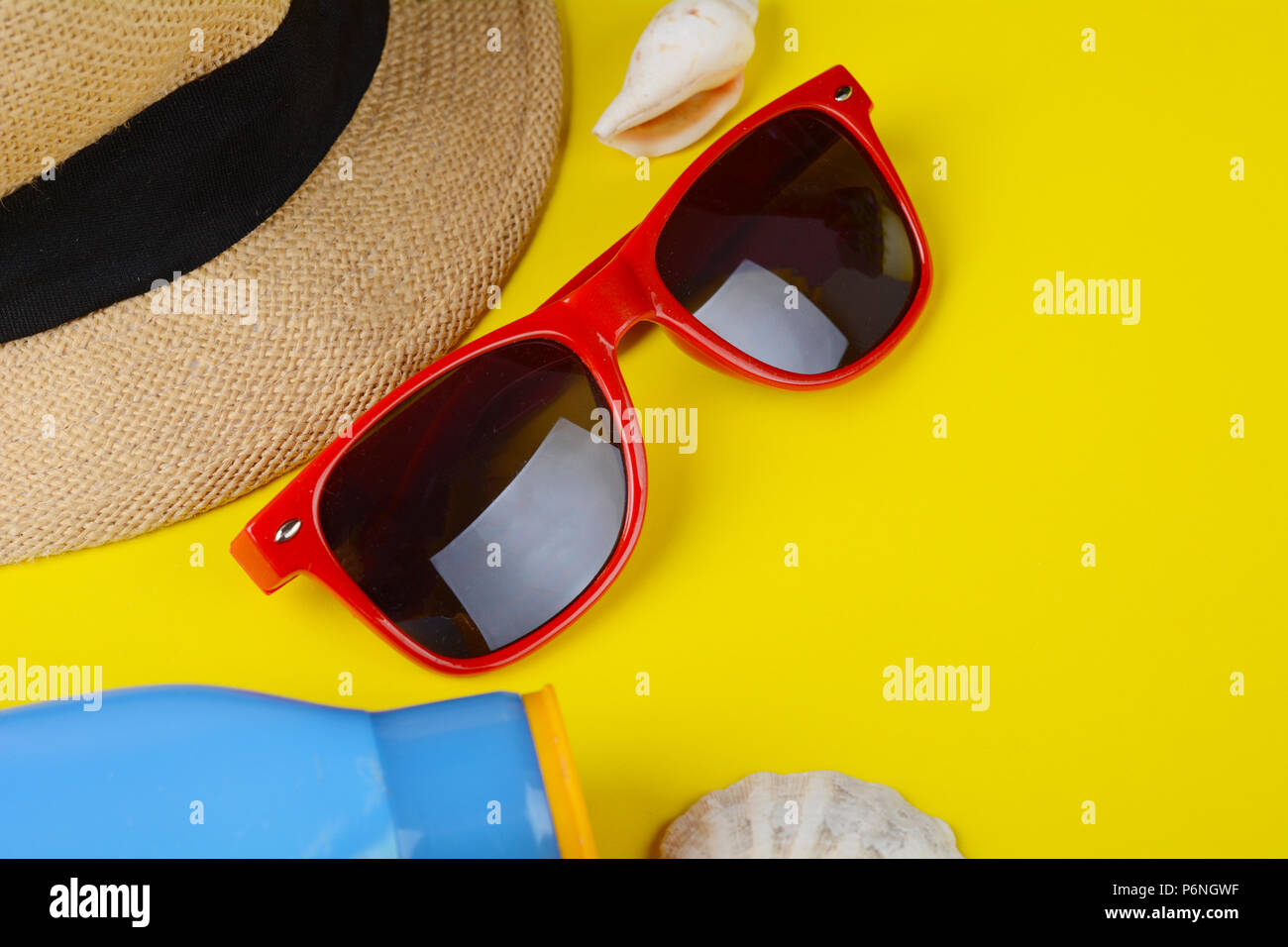 Top view of sunglasses, shells, starfish and sunblock on yellow ...