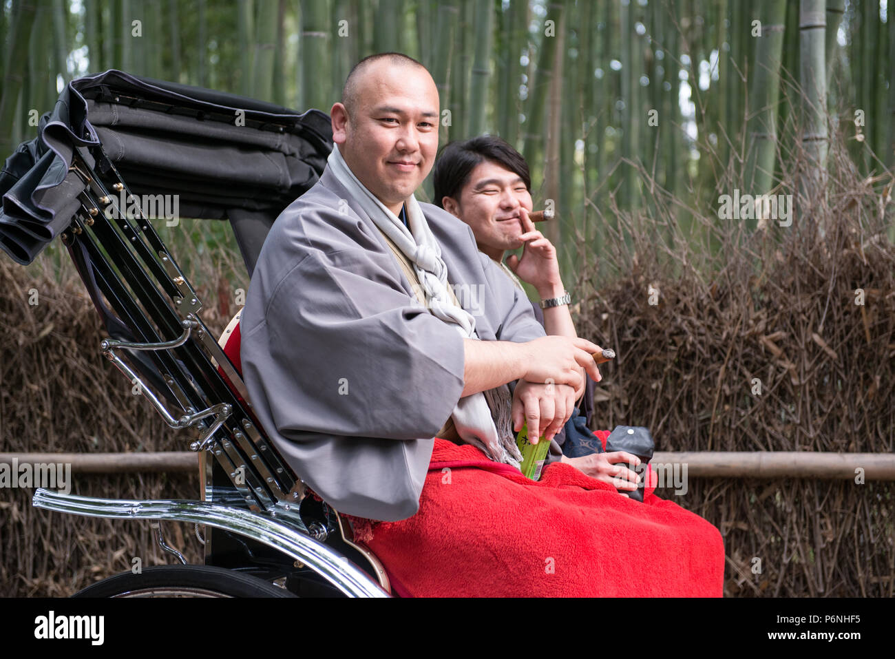 Japanese tourists smoking cigars in a traditional hand pulled rickshaw ...