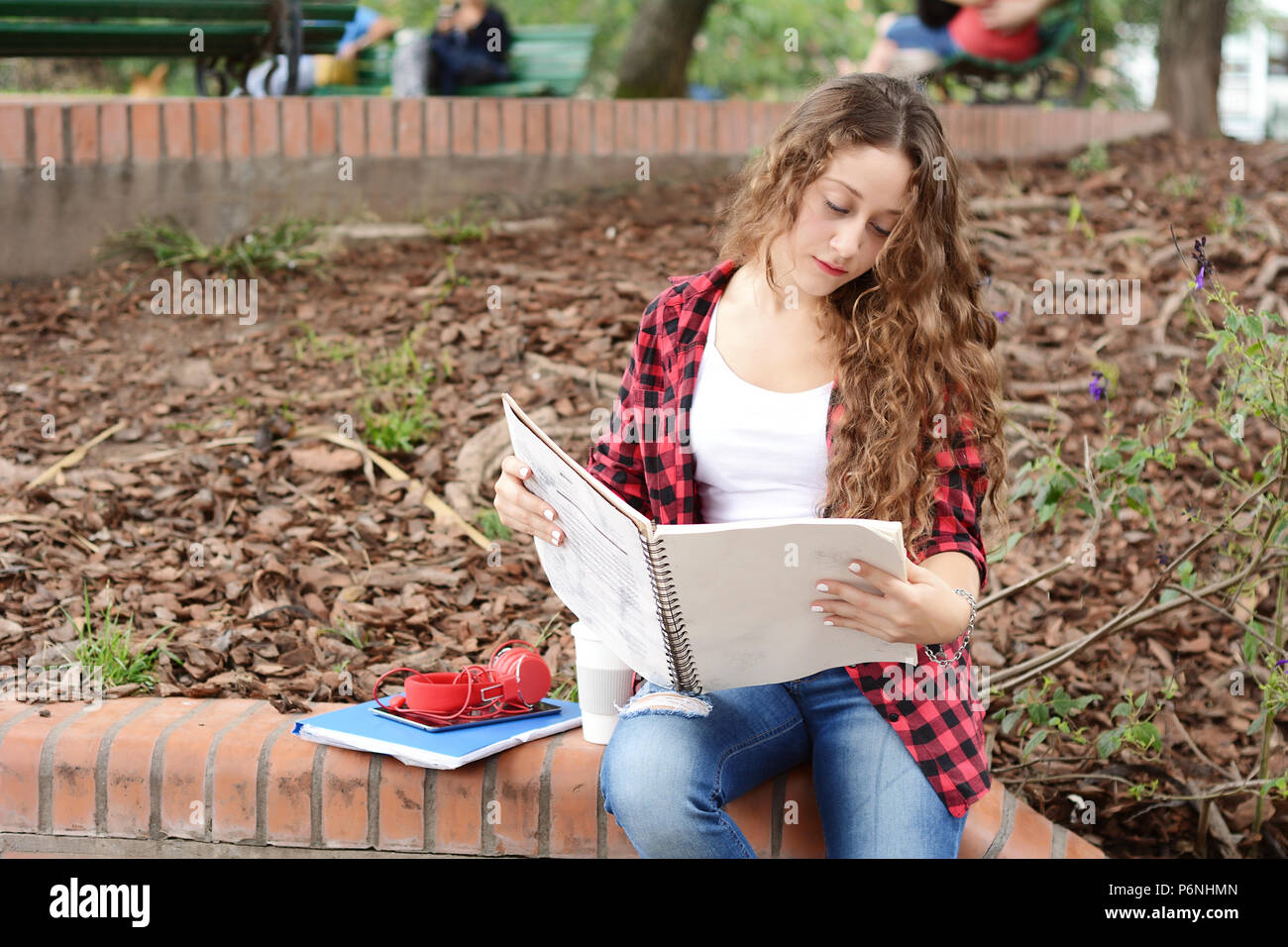 Young female student relaxing outdoors in the park with tablet, coffee ...