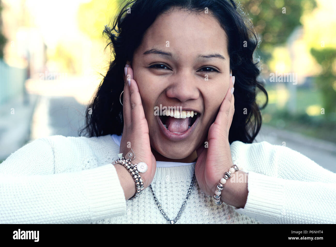 Outdoor portrait of a young beautiful latin woman with surprised facial expression. Outdoors ...