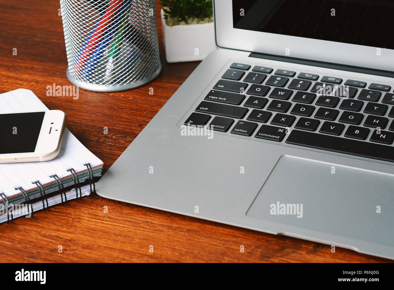 Close up view of keyboard and phone with black screen on wooden desk ...
