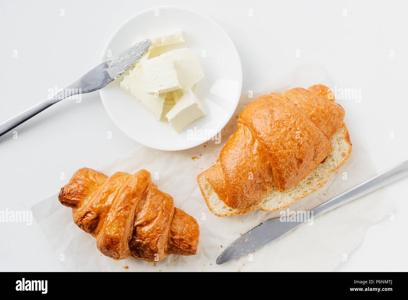 two croissants and butter on a white table, top view. French Breakfast ...