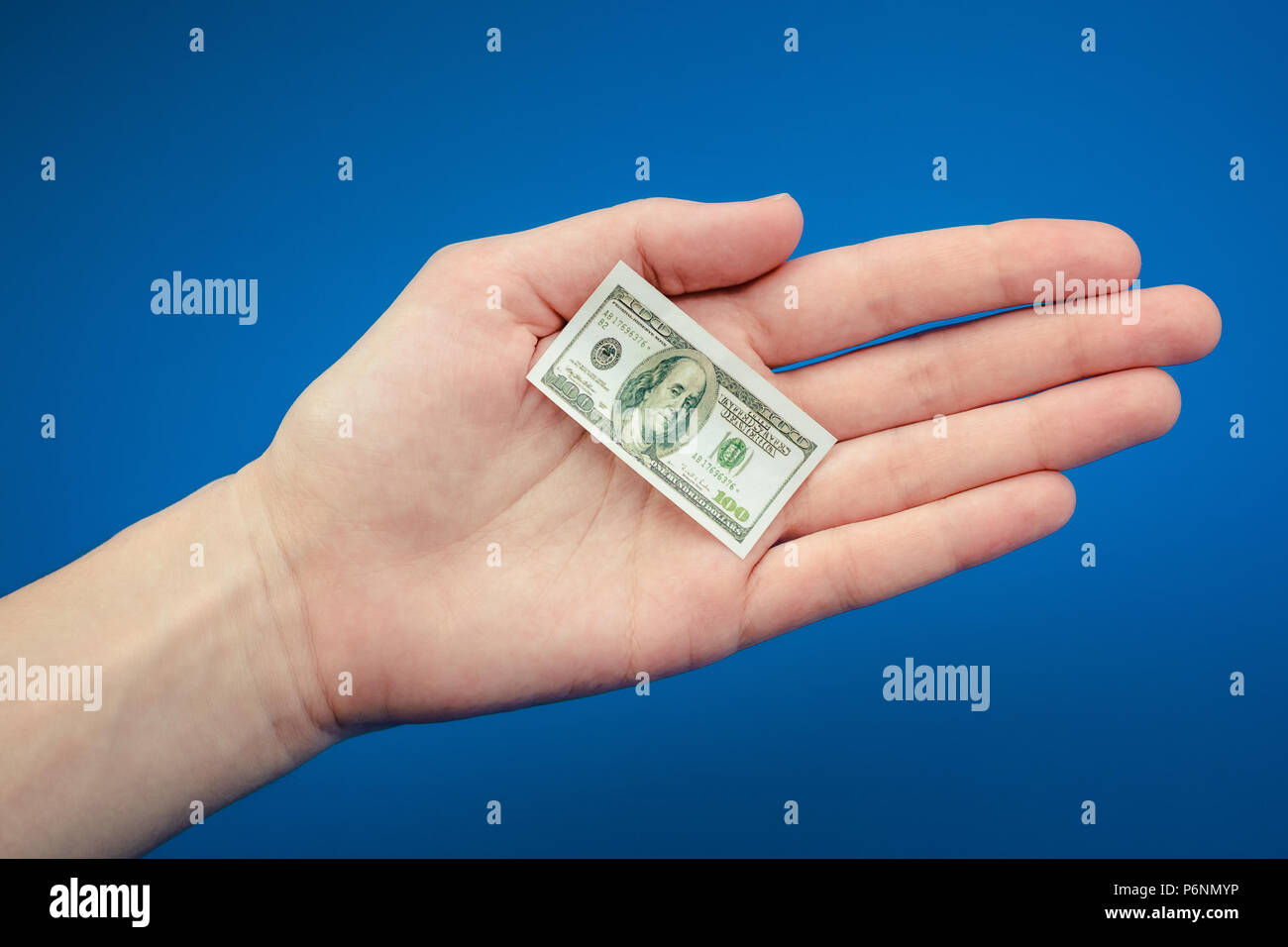 small American dollar bill in hand on a blue background. The concept of ...