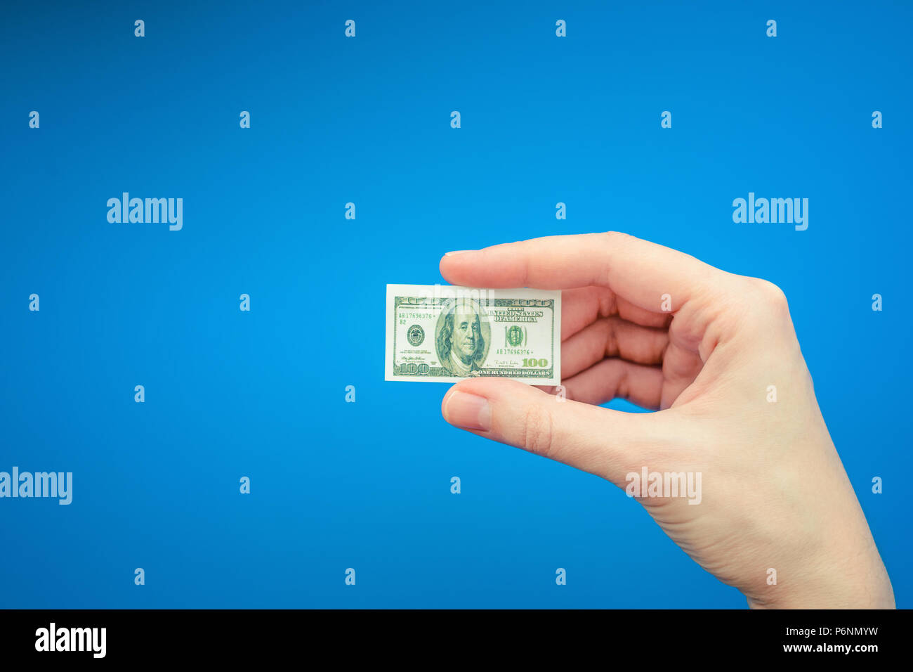woman's hand holding small banknote of US dollar, blue background close ...