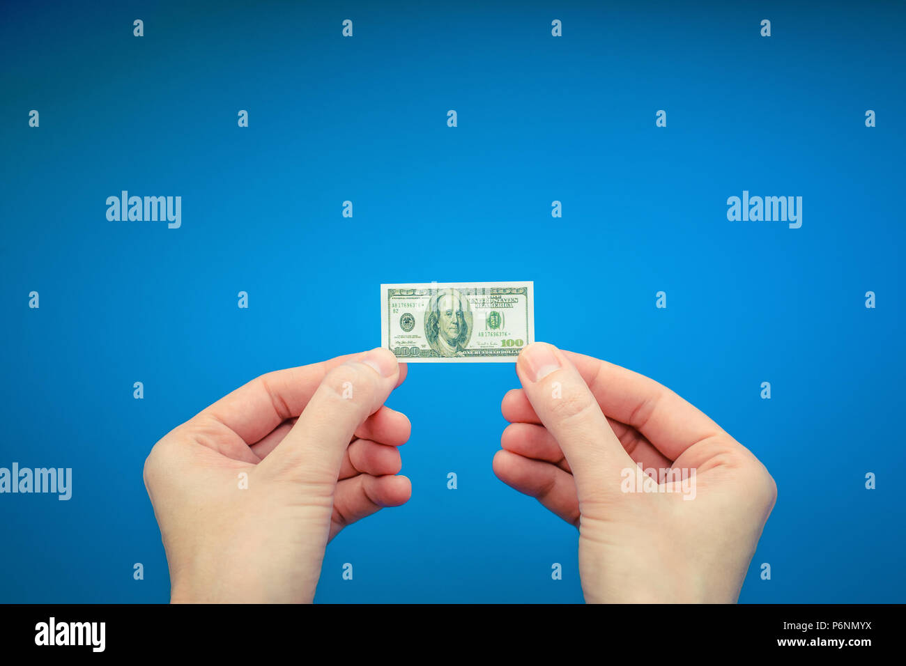 two woman's hands holding small banknote of US dollar, blue background ...