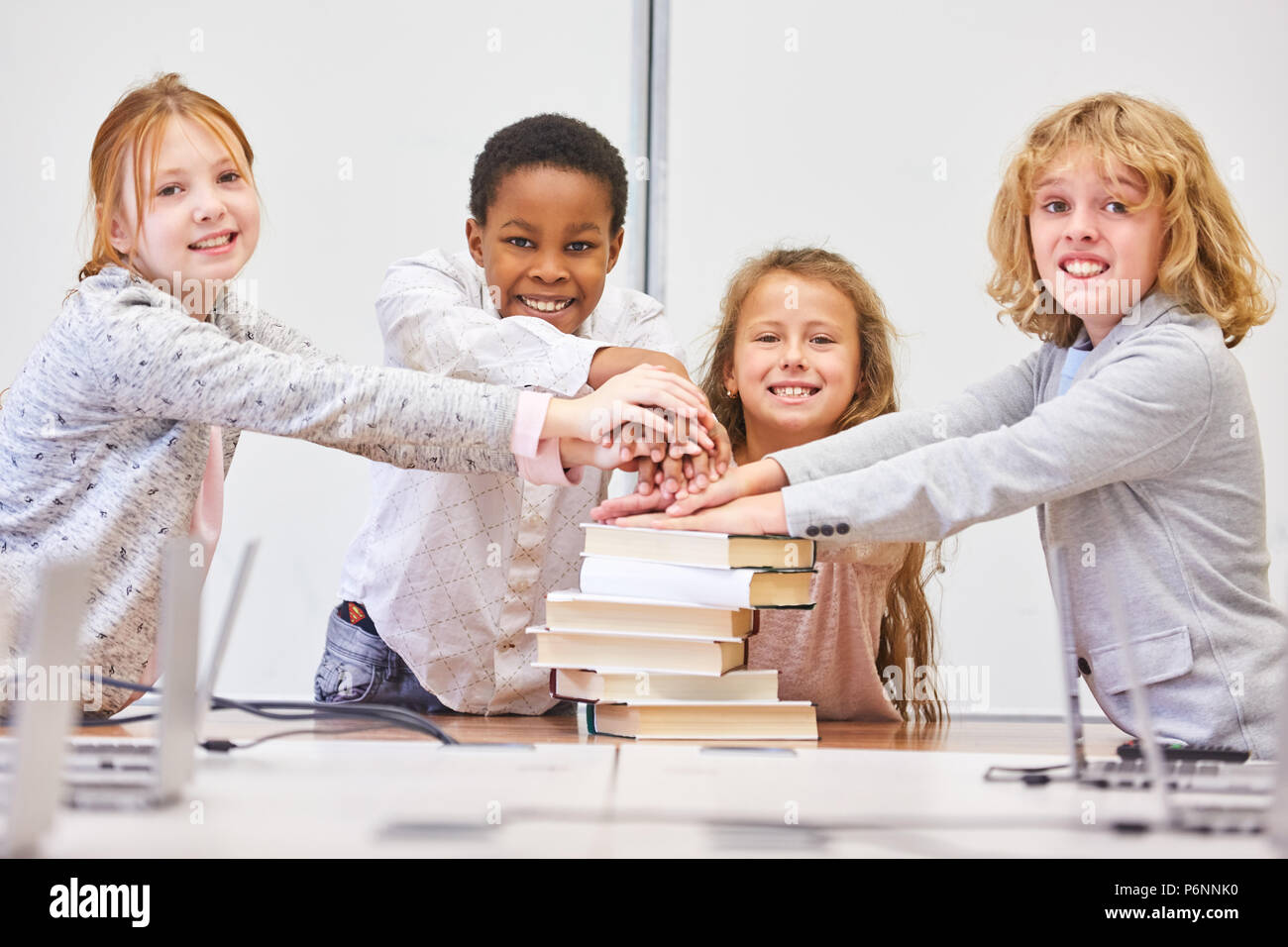 Children as elementary students pile up hands for teamwork and ...