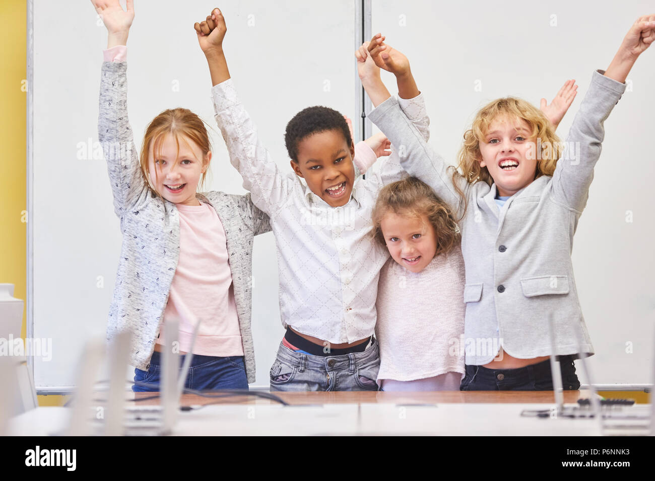 Group of kids as students cheer together about a success in elementary ...