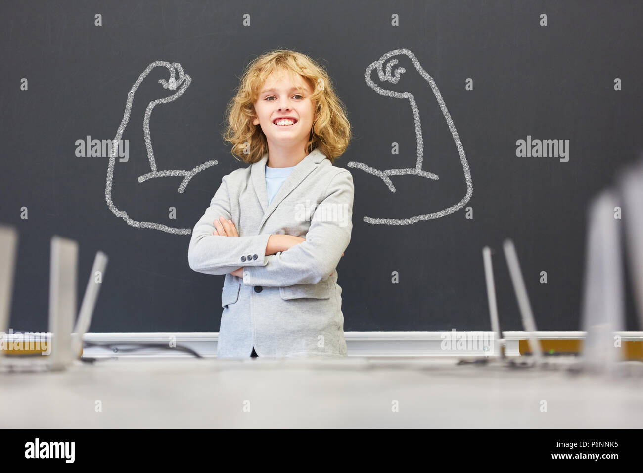 Strong boy in school with muscles at the blackboard in the classroom ...