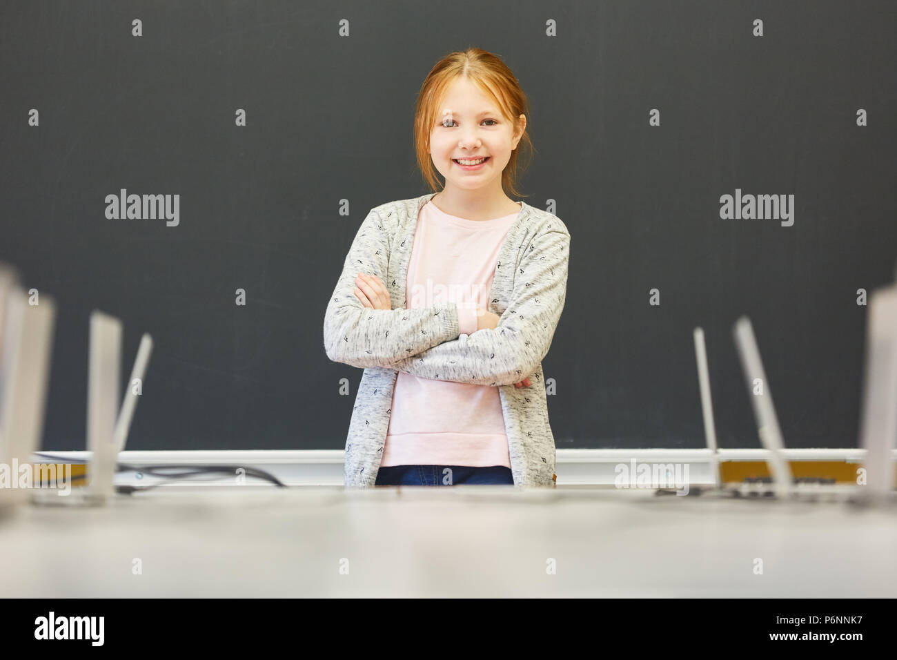 Proud student stands with crossed arms in front of the blackboard in ...