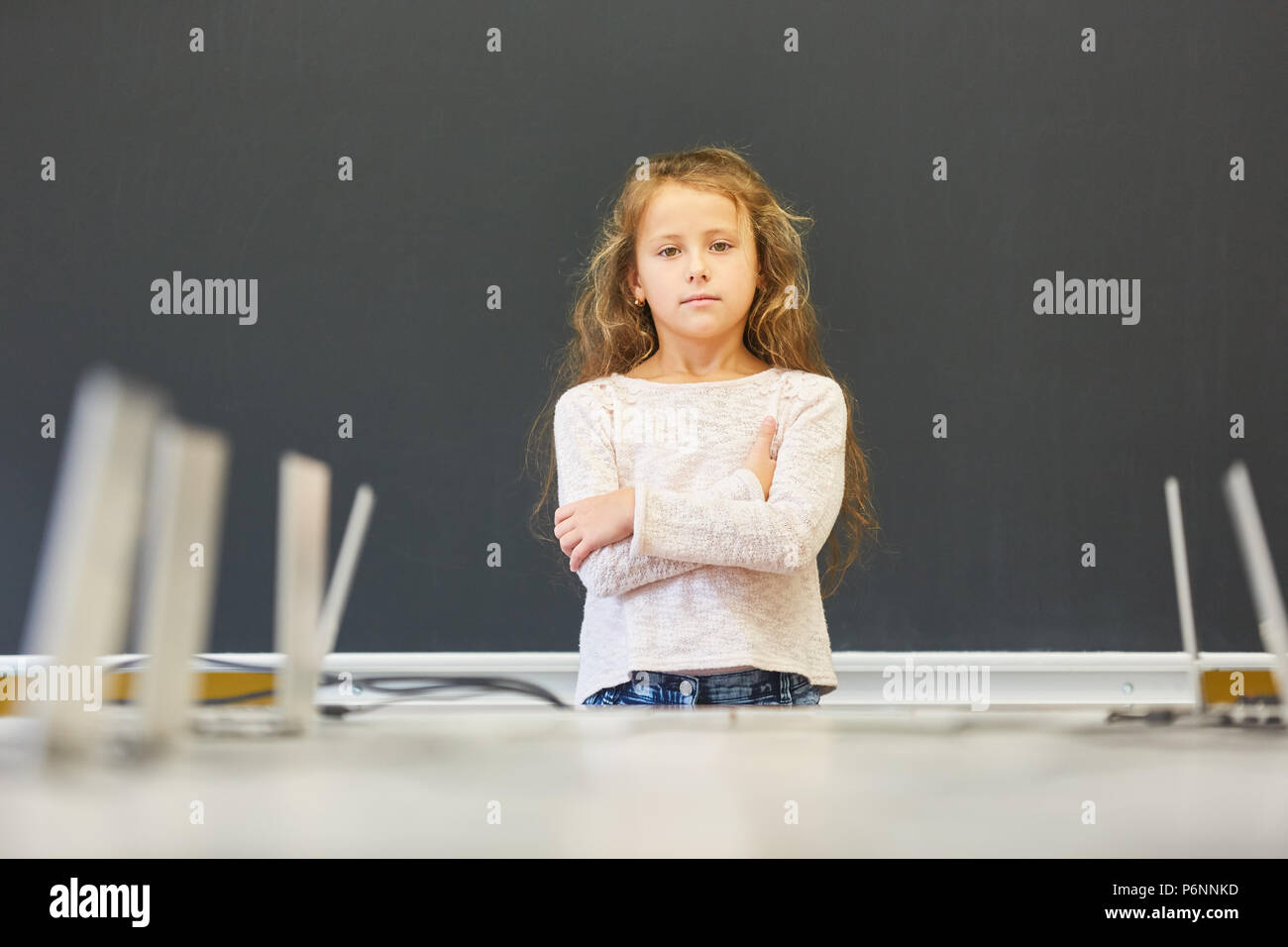 Girl as a student stands with crossed arms in elementary school at the ...