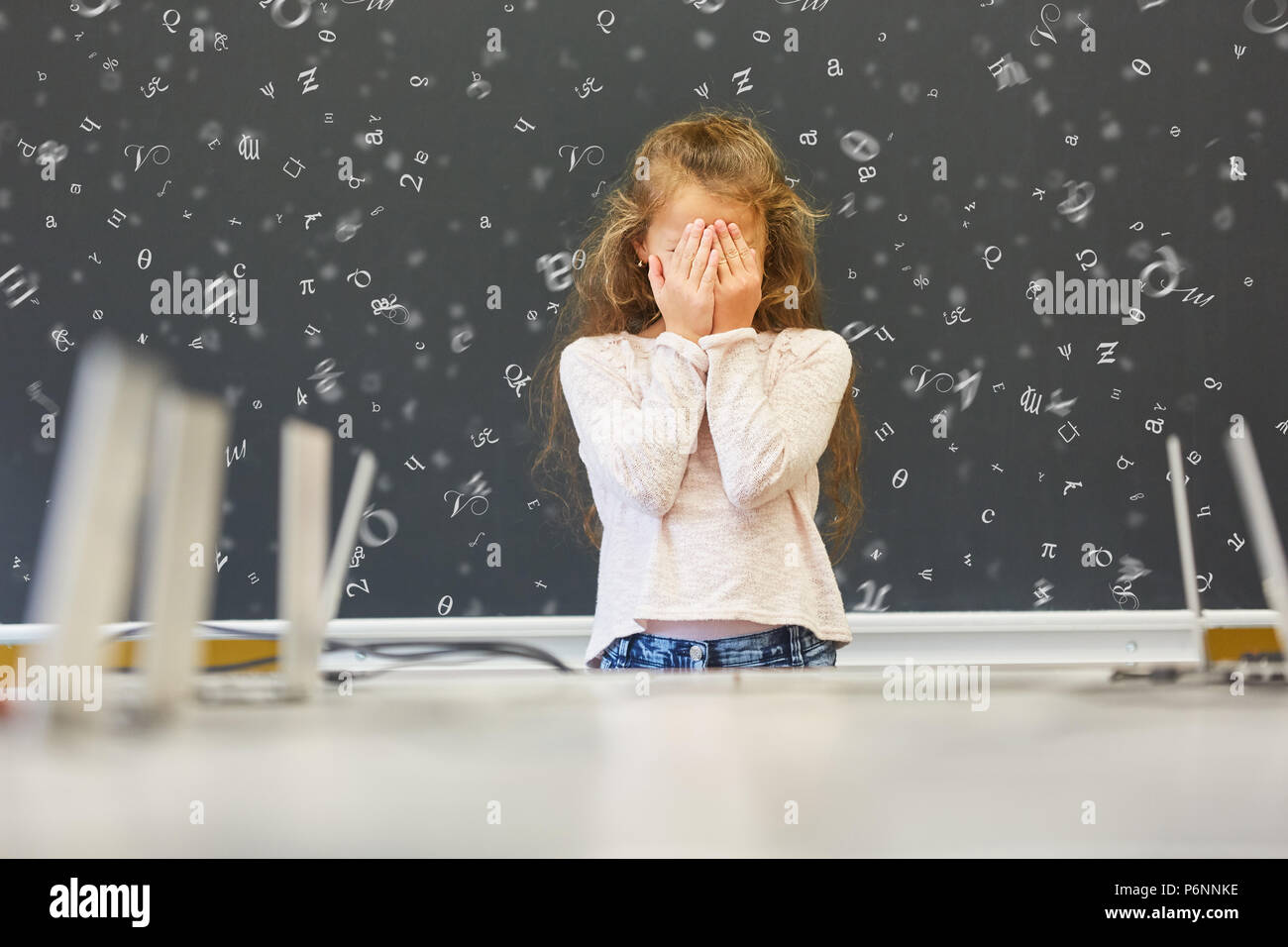 Child with reading difficulties in school in front of blackboard with ...