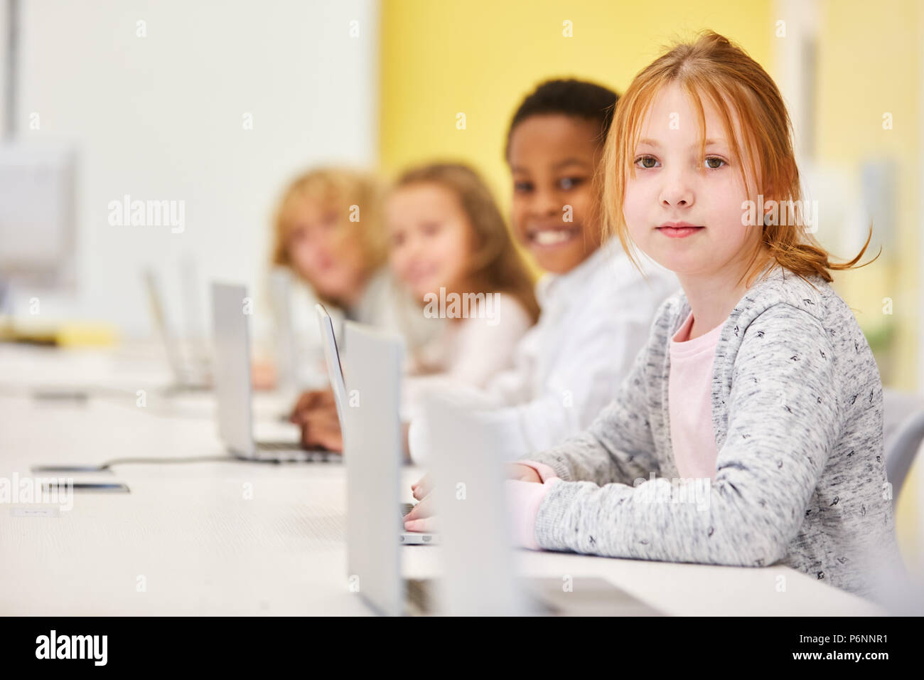 Group of kids in elementary school using laptop together in computer ...