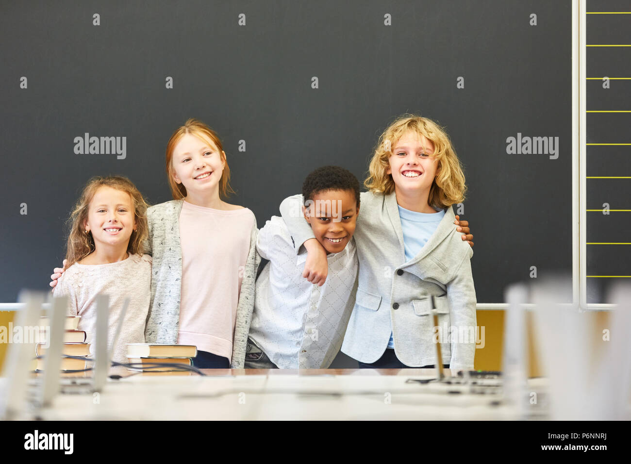 Four cheerful children in multicultural school as friends in front of ...