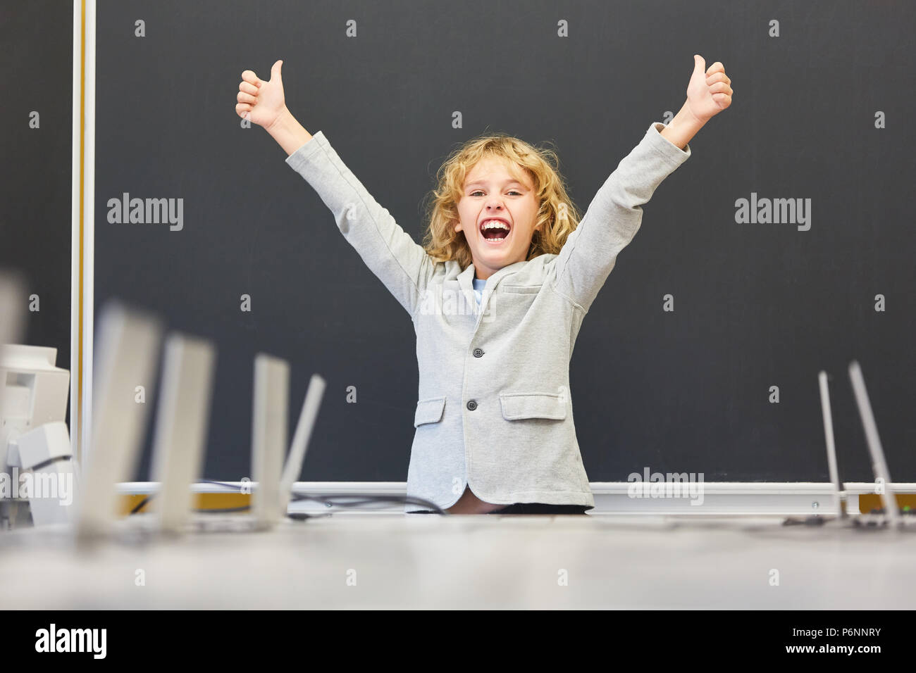 Blond boy as a student cheers at the elementary school blackboard in a ...