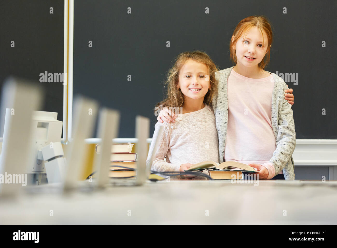Two girls as girlfriends learn and hold together in elementary school ...