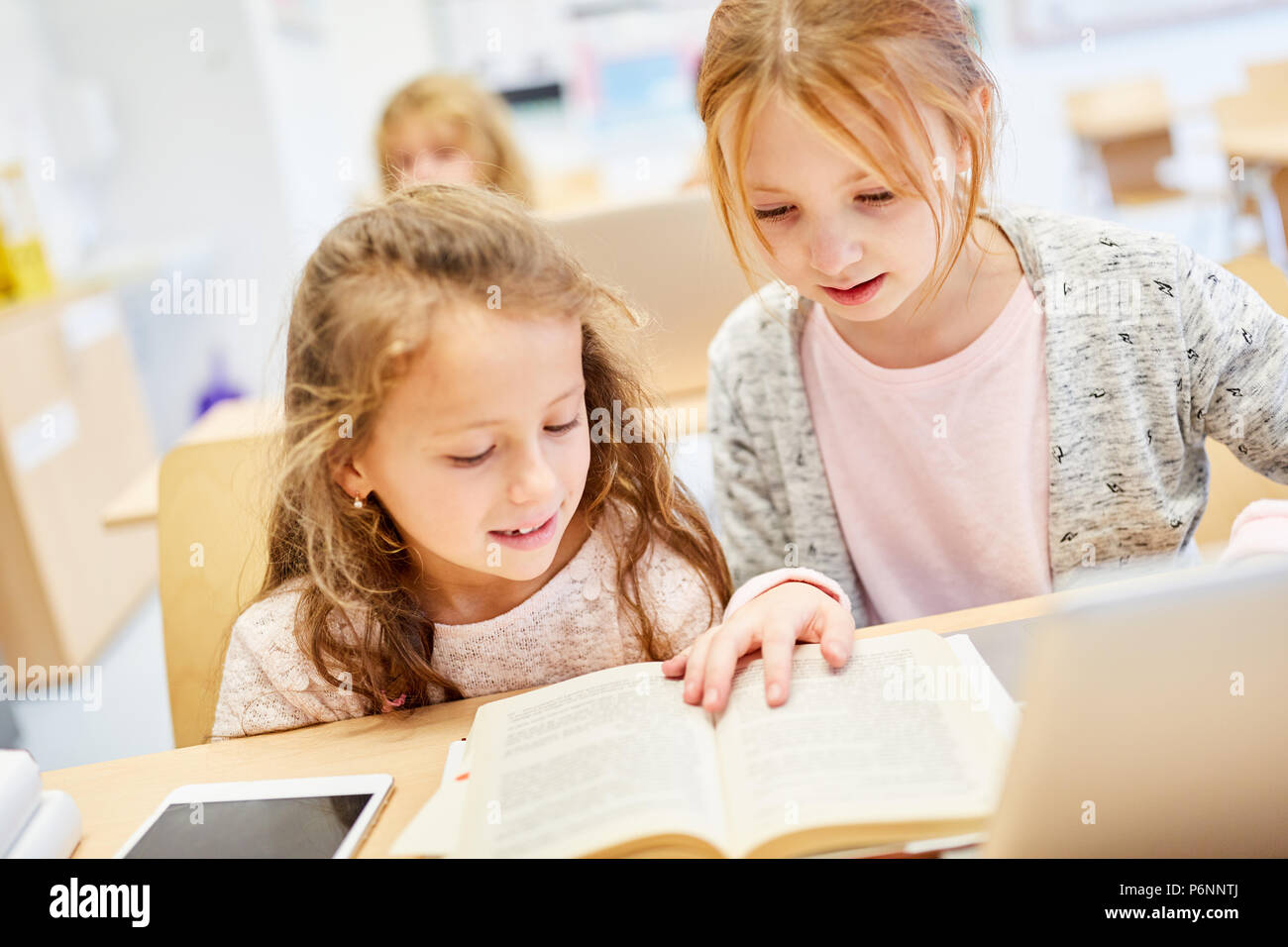 Two girls as students in class learn in teamwork in elementary school ...