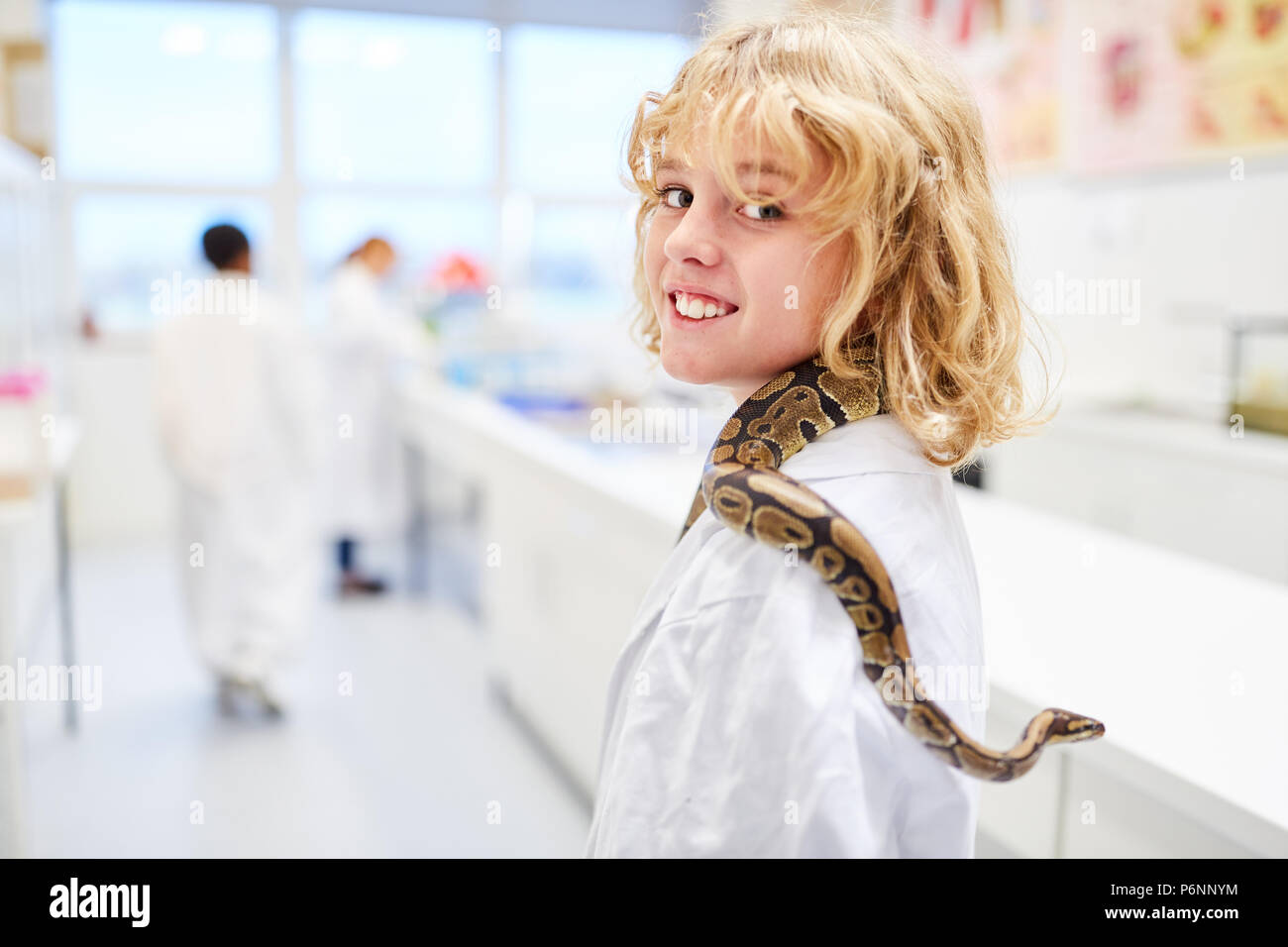 Boy strokes a snake on his shoulder in the elementary school biology ...