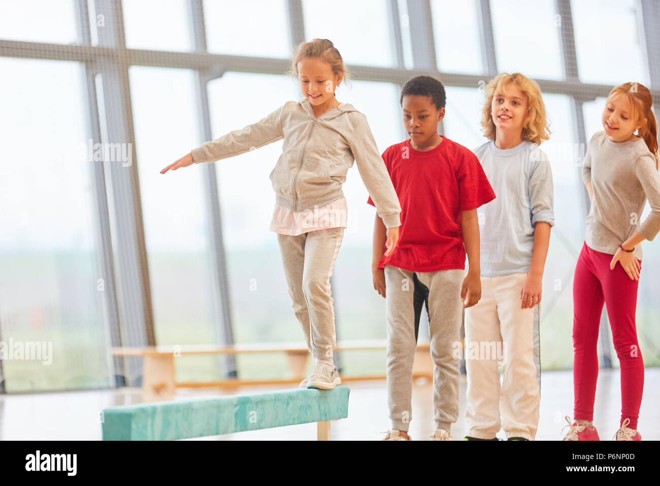 Sporty students balance on a balance beam in physical education Stock ...