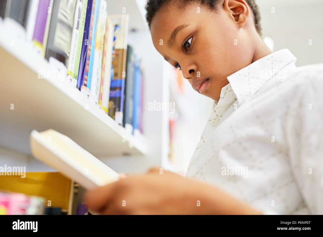 African student attentively reads in a book in the school library Stock ...