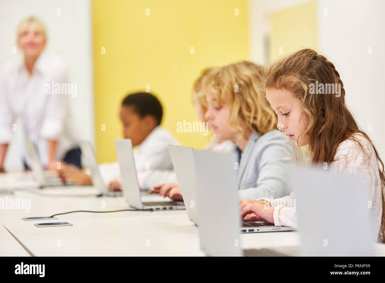 Children at the laptop in a computer class of a primary school learning ...