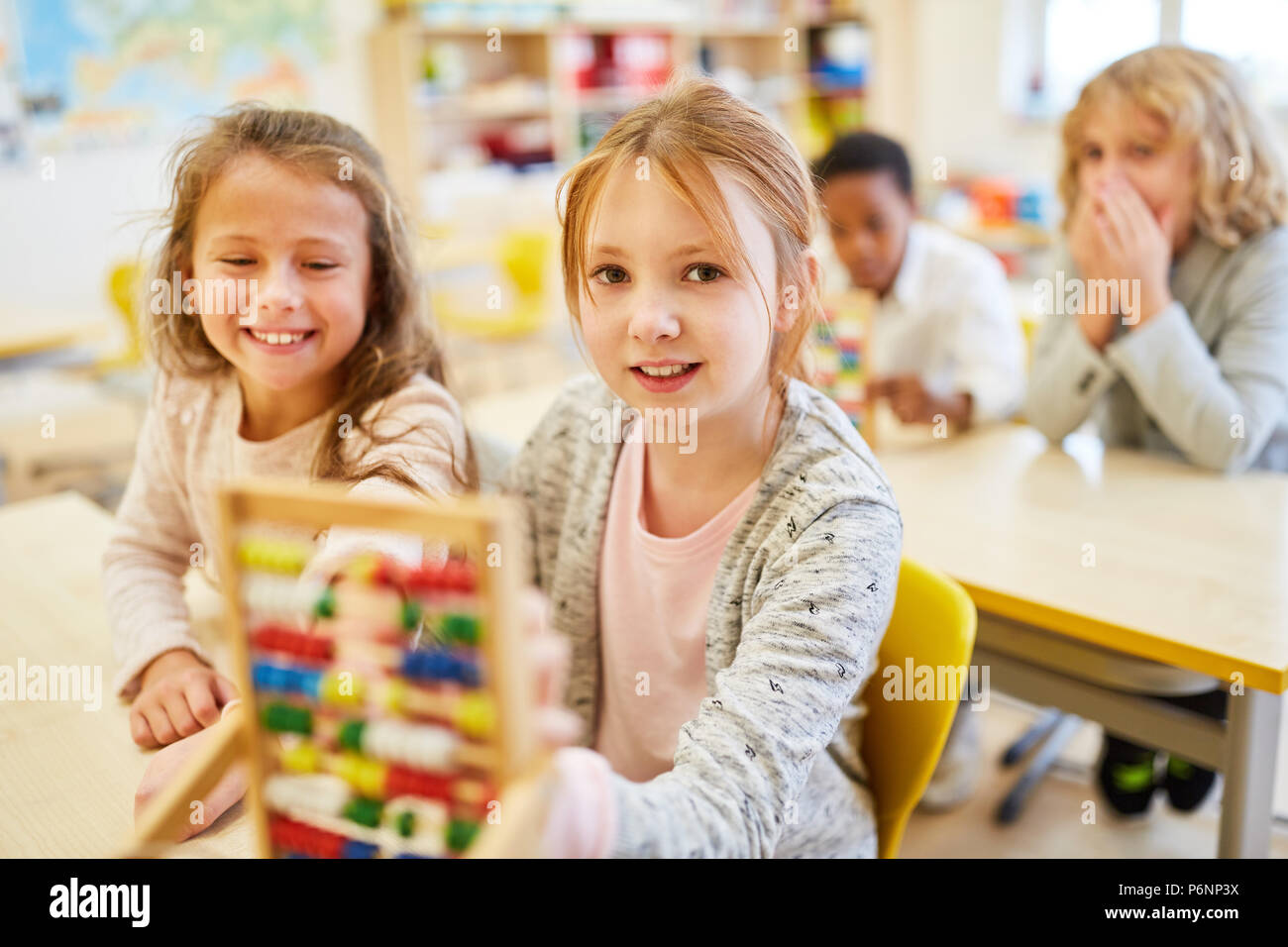 Two girls studying as a student in math class are calculating with an ...