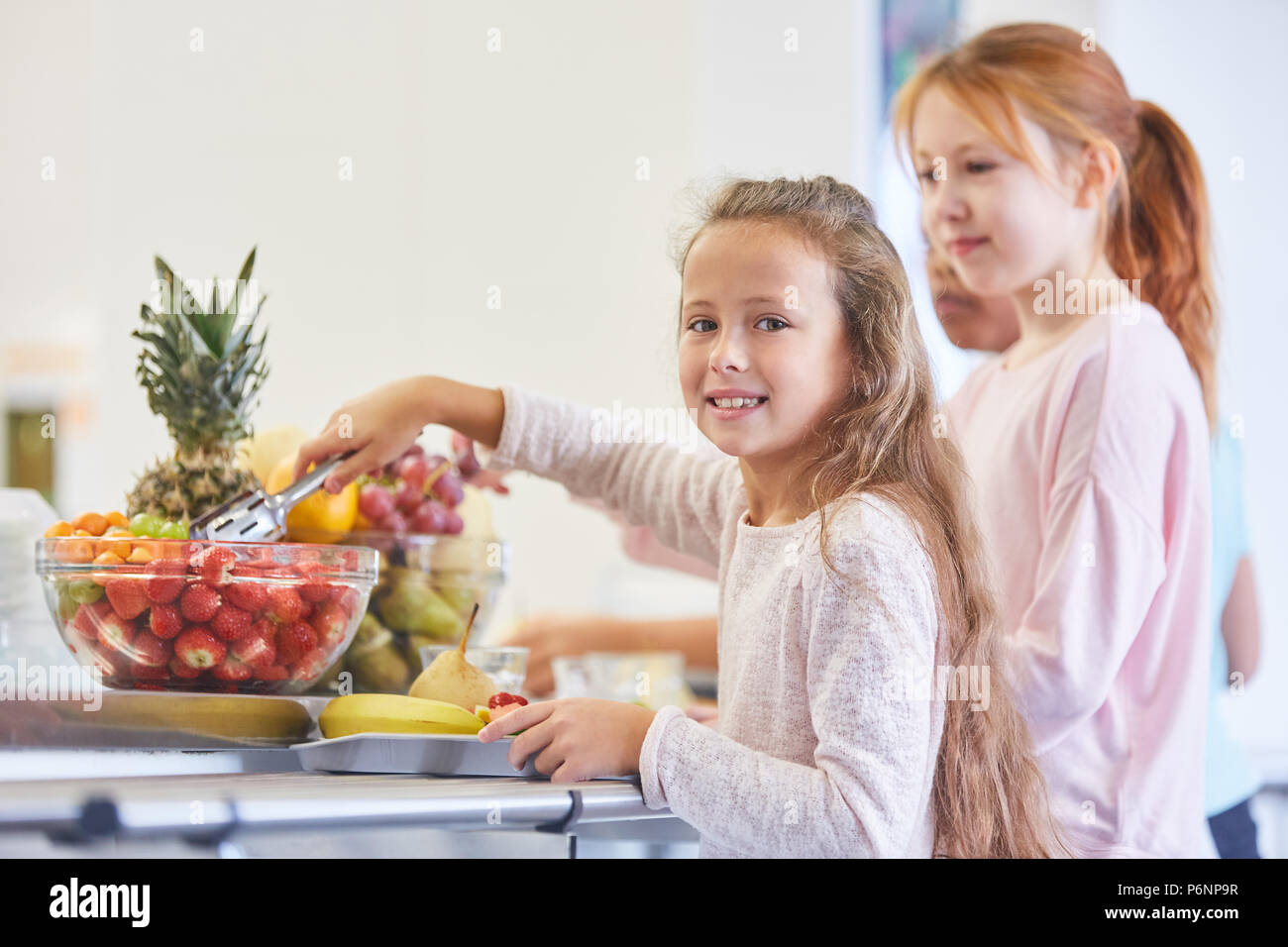 Girls and other children take fruits from the buffet in elementary ...