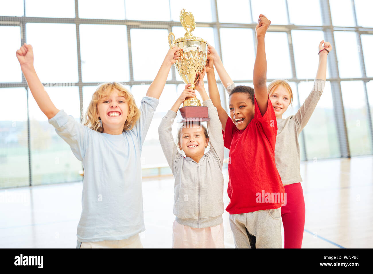 Group of kids as successful team with cup cheers after a competition ...