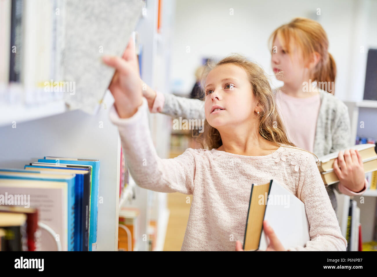 Girl as a student doing research in the library of elementary school ...