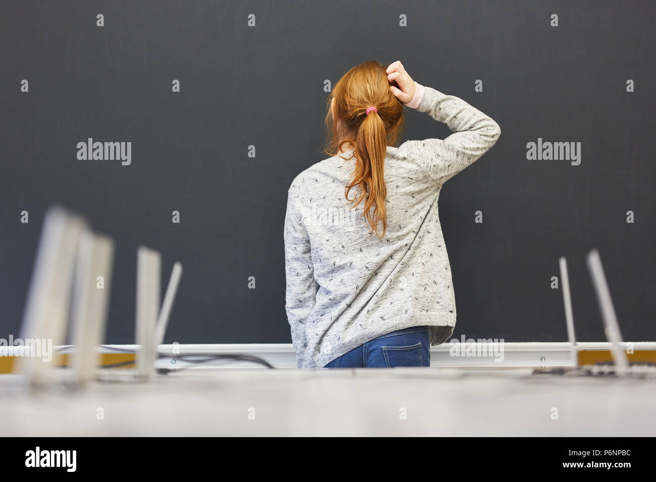 Child as a pupil at elementary school empty board reflects on a problem ...