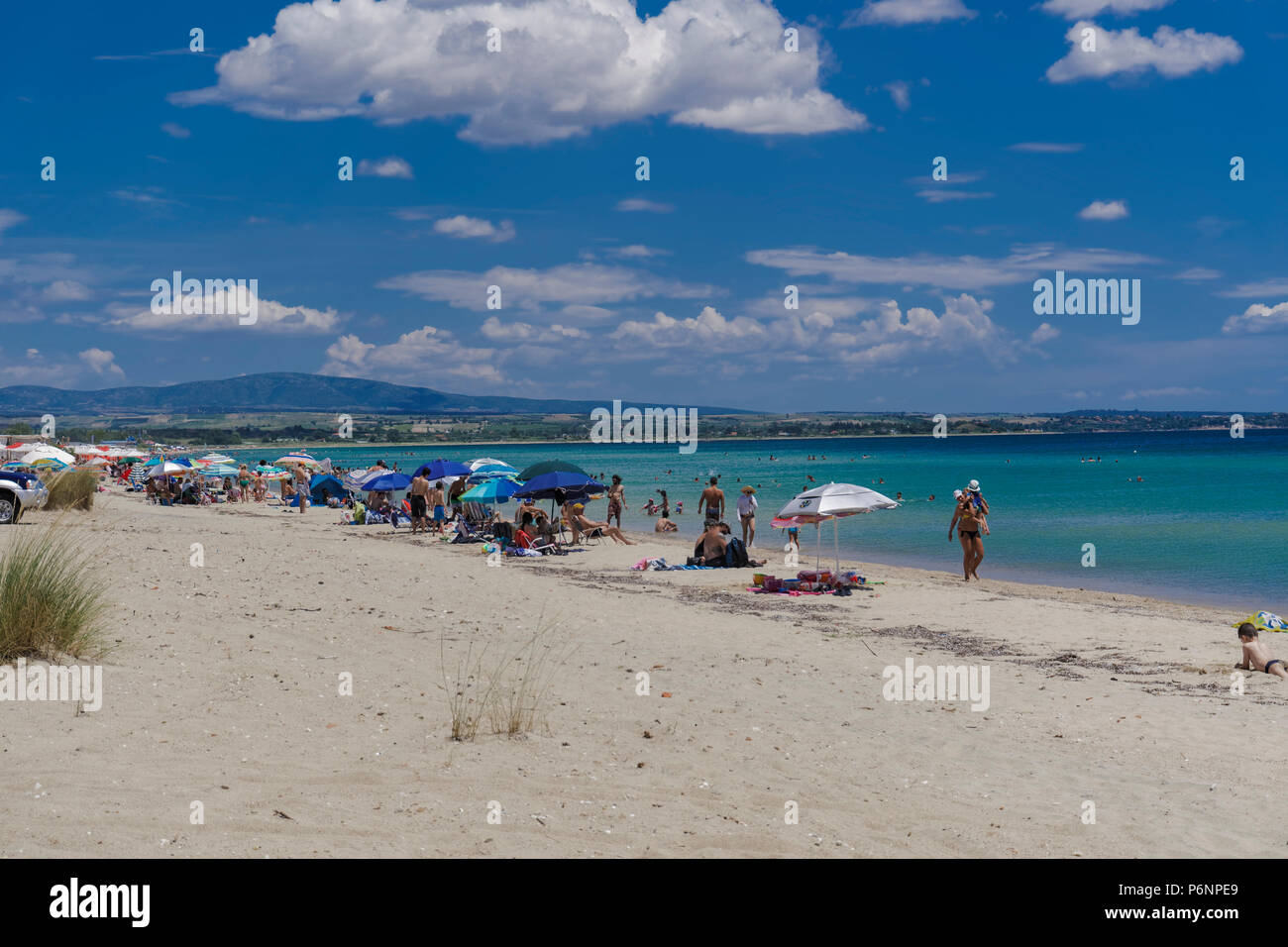 Greek Mediterranean beach with crowd. Bathers resting on beach chairs ...
