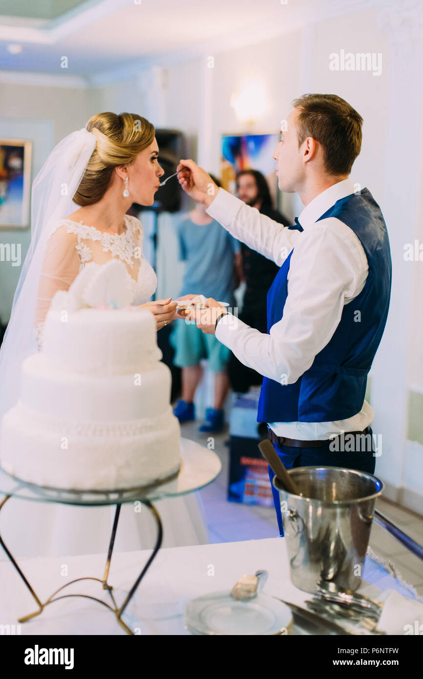 The groom is feeding the bride with the wedding cake Stock Photo - Alamy