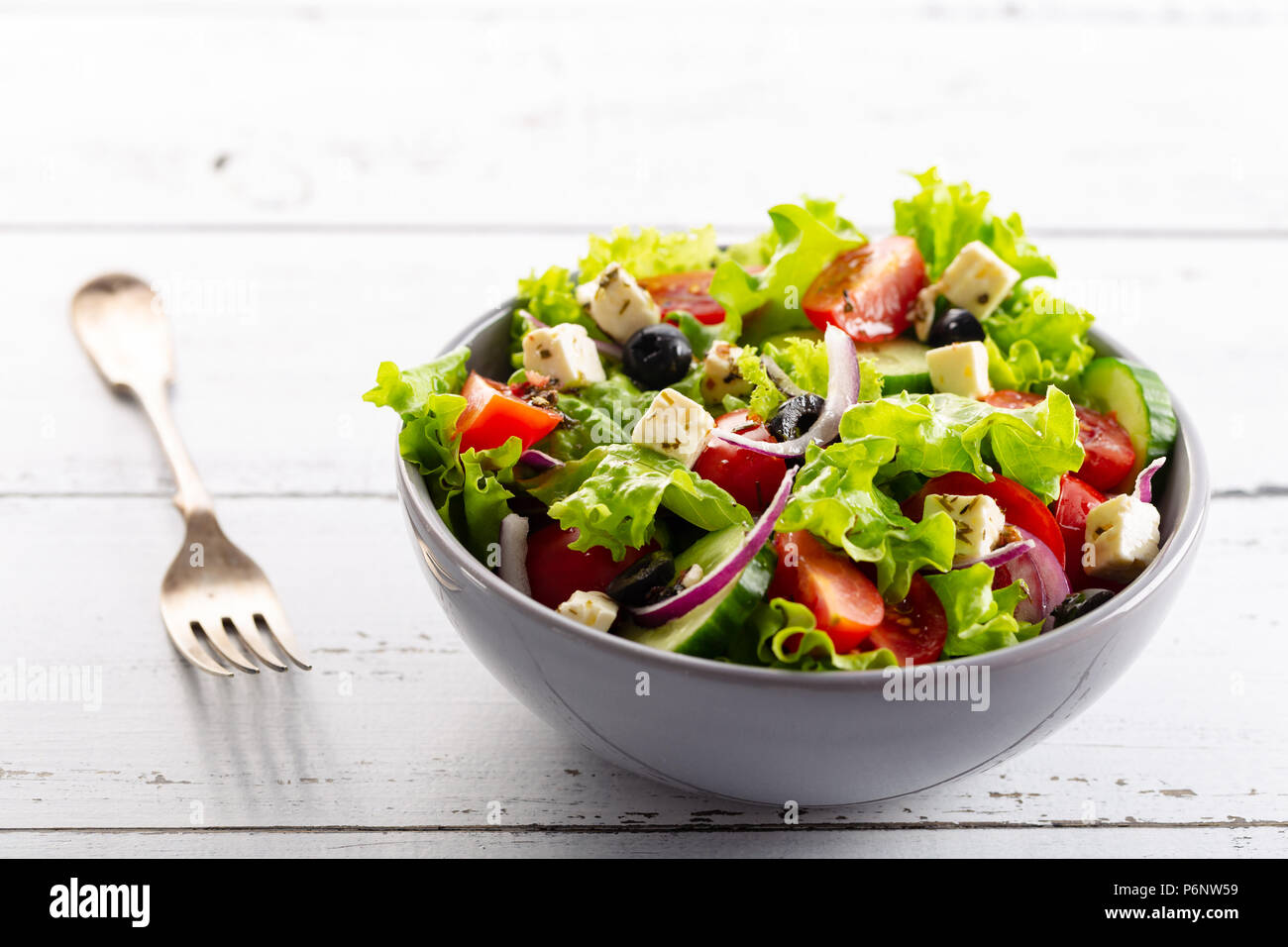 Fresh greek salad served in bowl with fork Stock Photo - Alamy