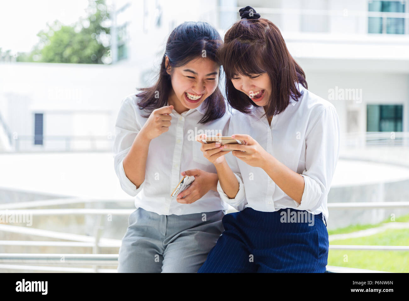 Two young happy Asian women having fun playing social media game on ...