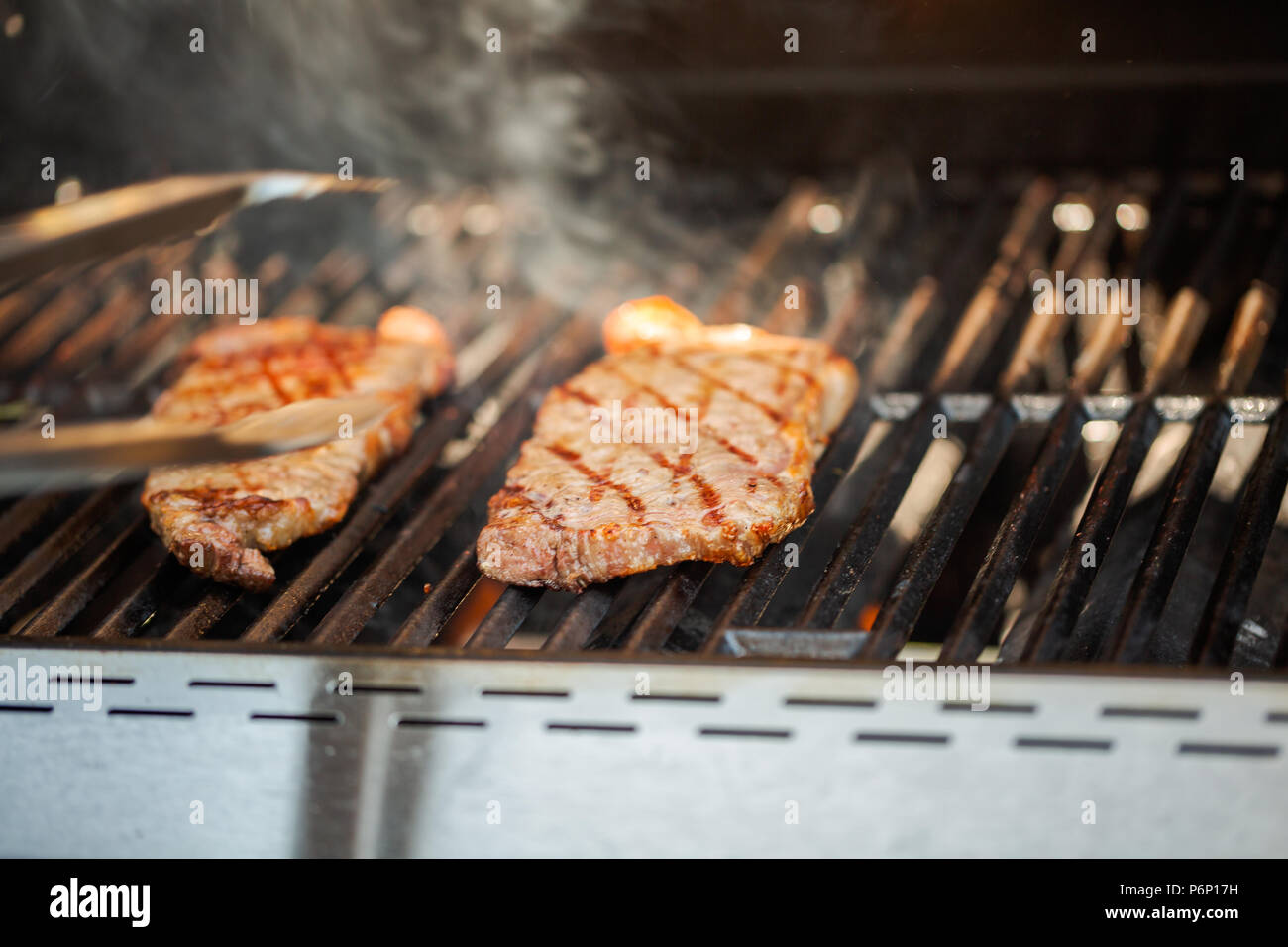 Step by step. Grilling New York strip steak on outdoor gas grill Stock ...