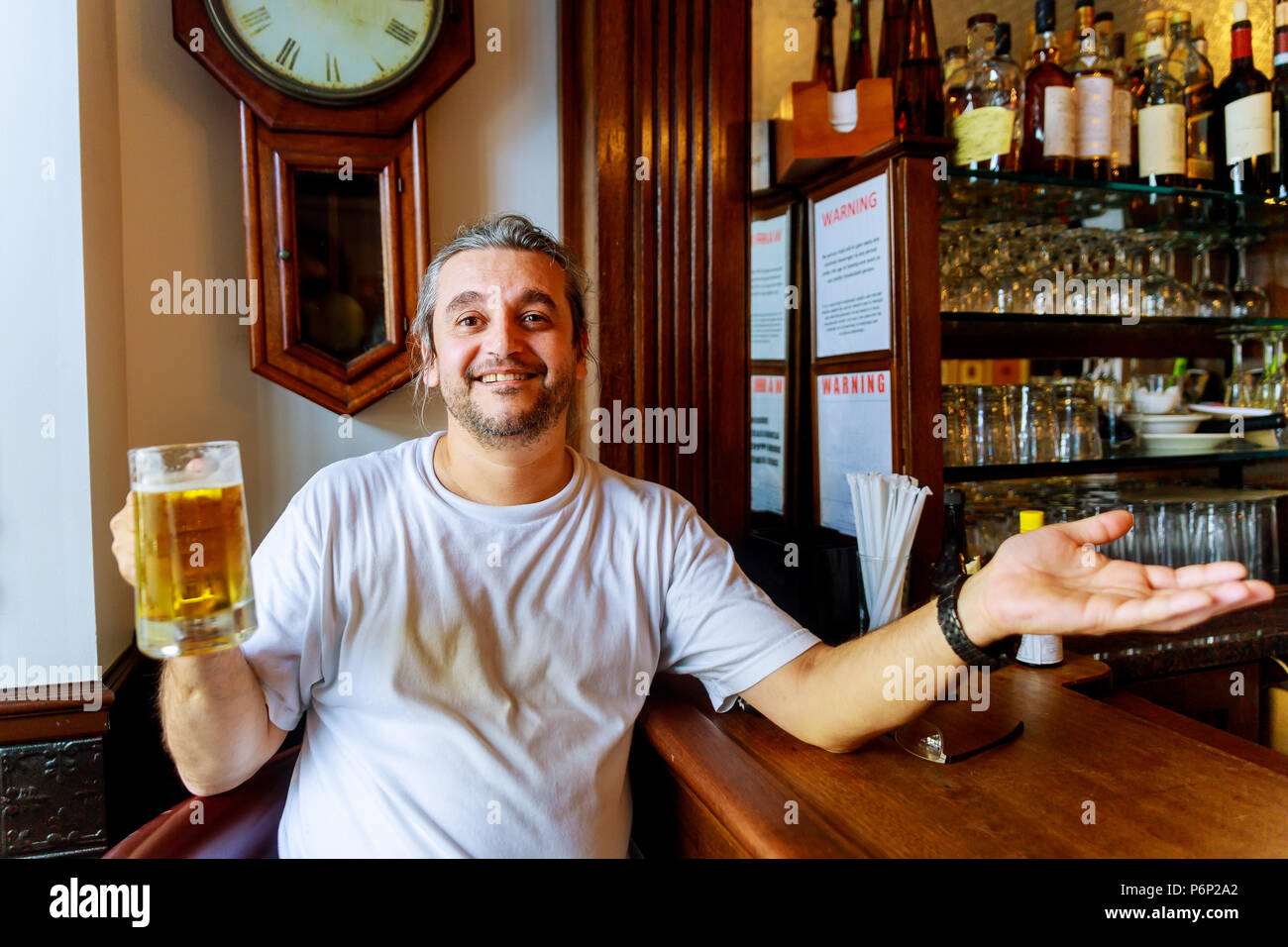 Attractive man holding an half-pint of beer in casual clothes is ...