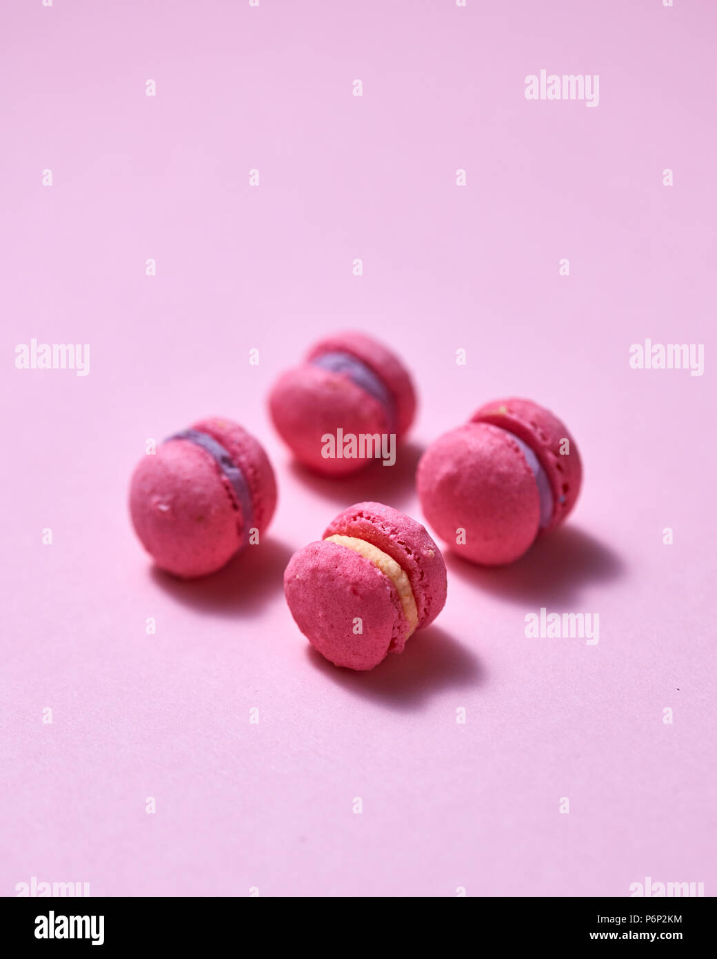 Top view of mini pink macaroons on soft sweet pink paper background ...