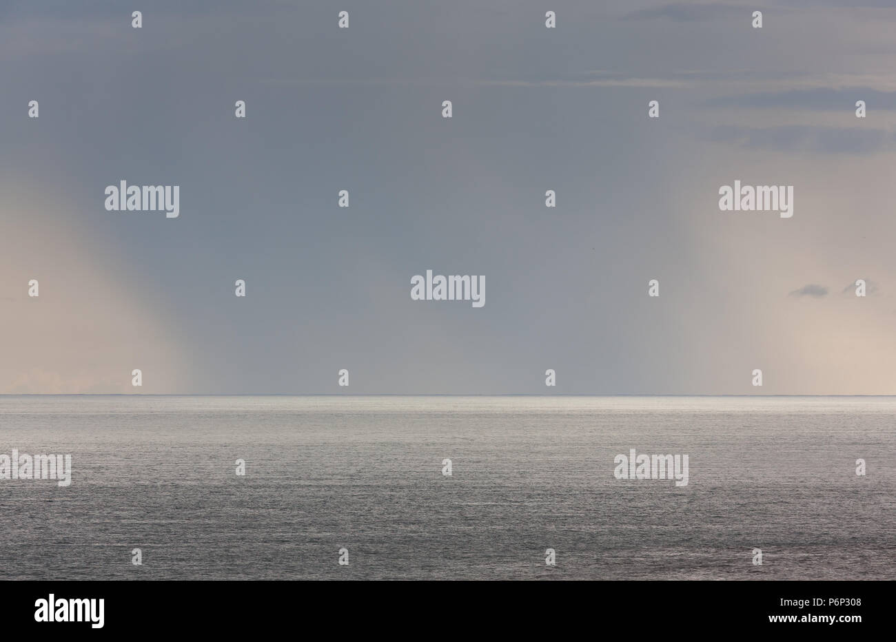 view of a band of rain falling on the ocean as the sun begins to set ...