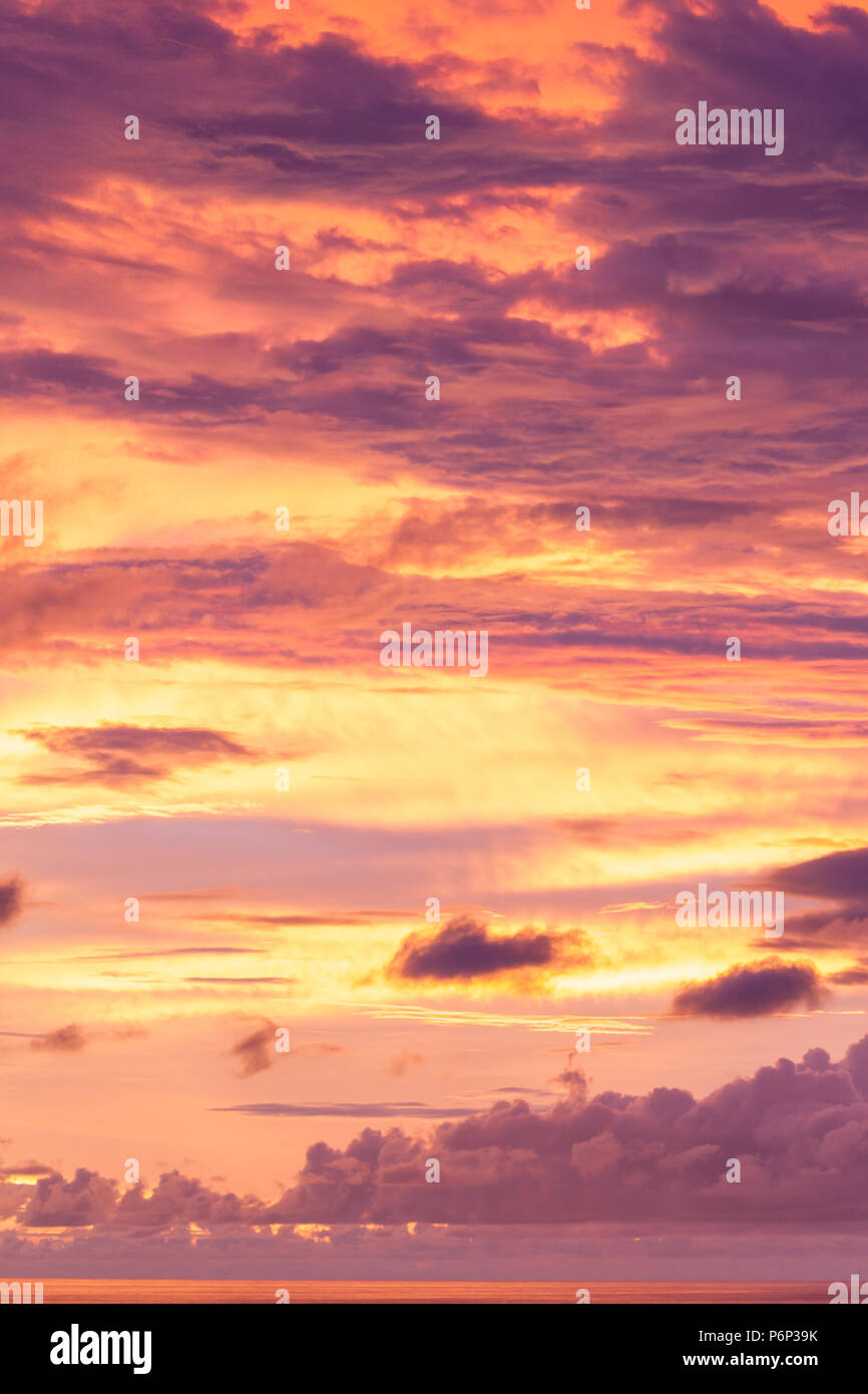 Vivid colors in the clouds and sky as the sun sets behind the horizon leaving a beautiful ...