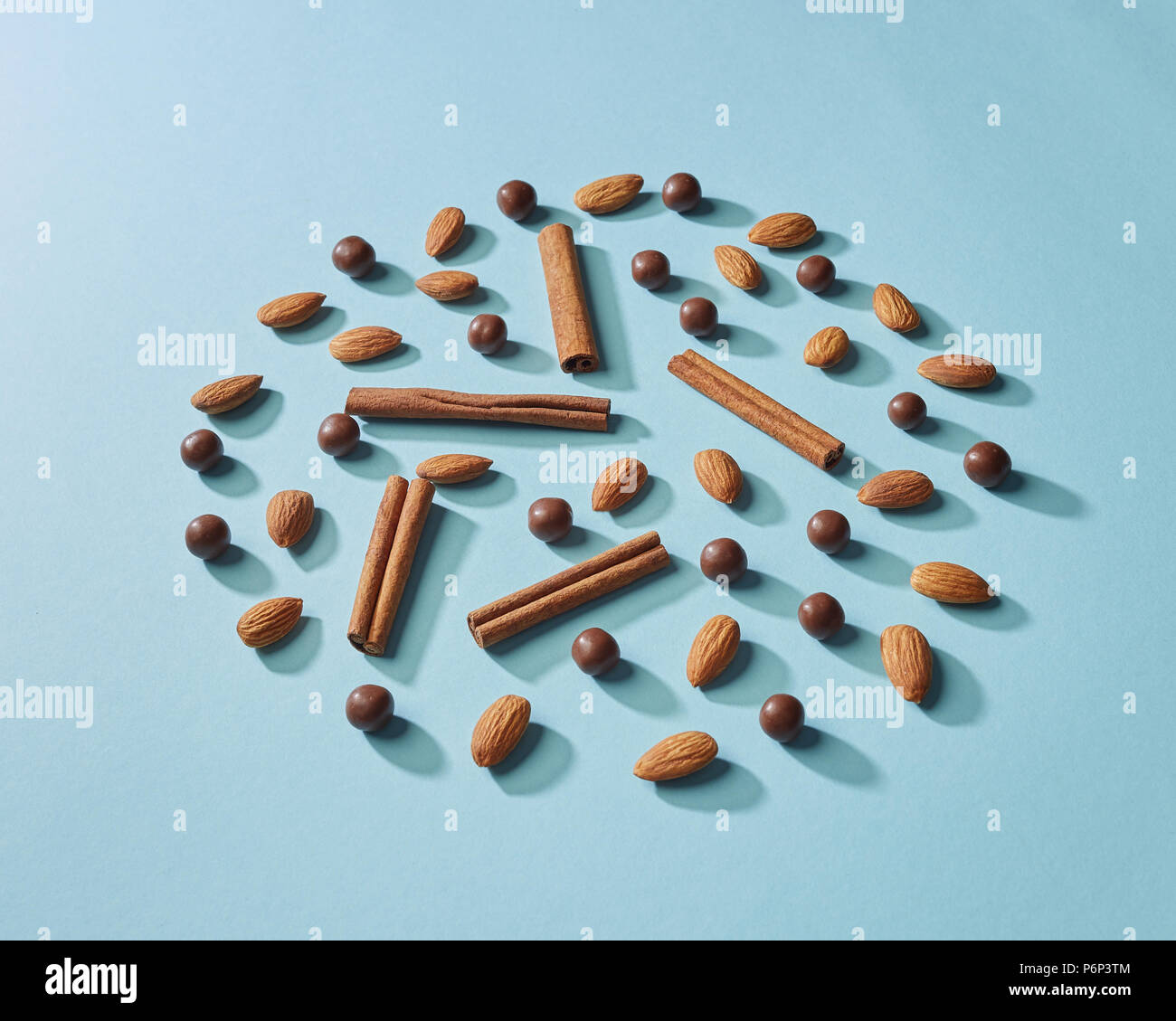 A pattern made in the shape of a circle of almonds, cinnamon sticks and ...