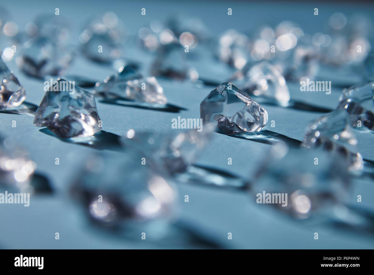 Various transparent ice cubes with reflection of shadows on a blue ...