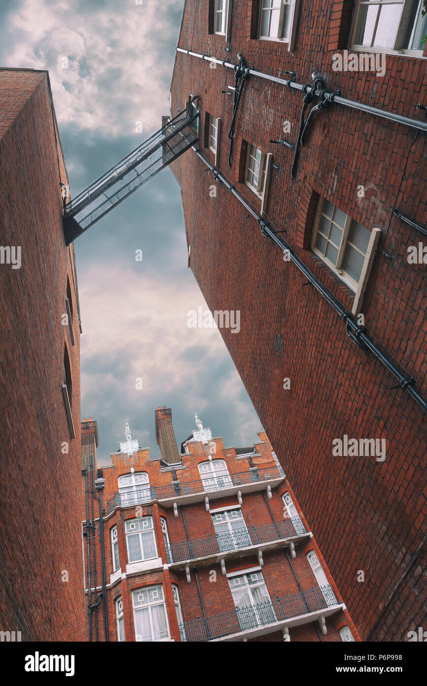 Facades of red brick houses and pipes on them against the sky in London ...