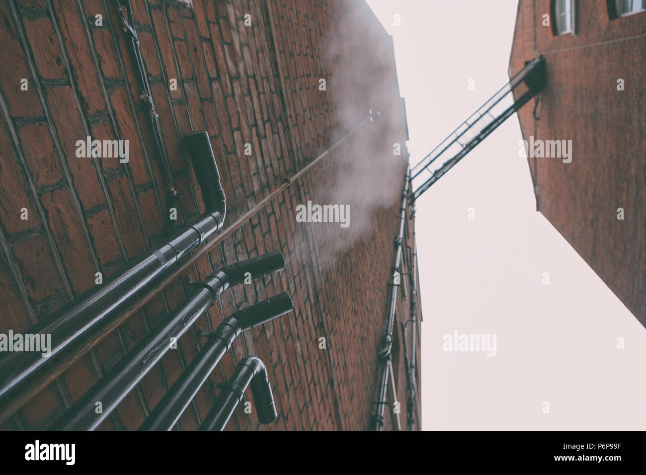 Facades of red brick houses and pipes on them against the sky in London ...