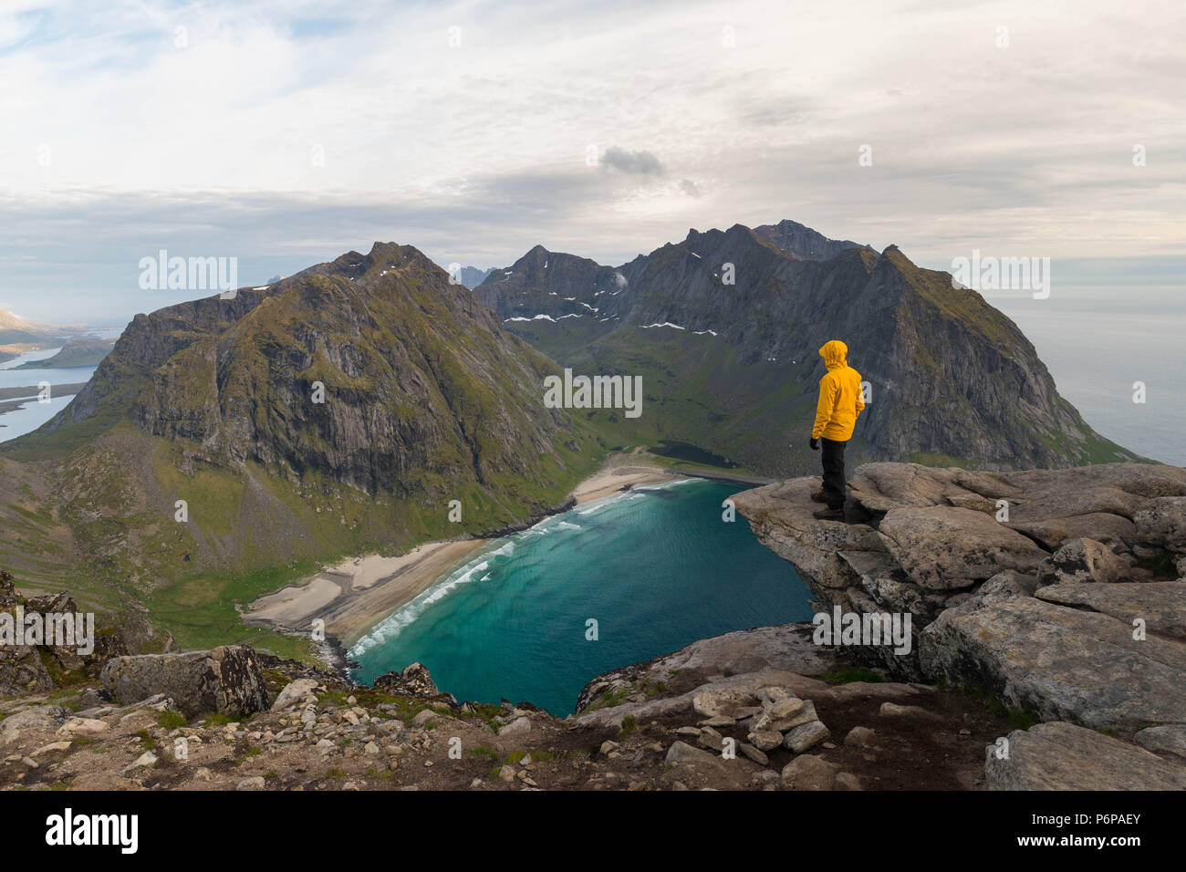 Hiker on the summit of Ryten, below is the famous Kvalvika beach ...